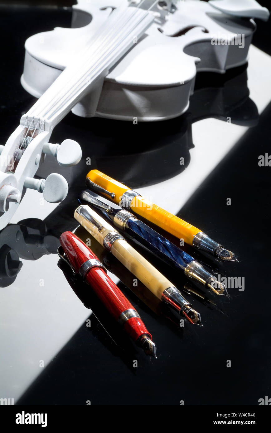 Four different pens and violin on a glass background Stock Photo - Alamy