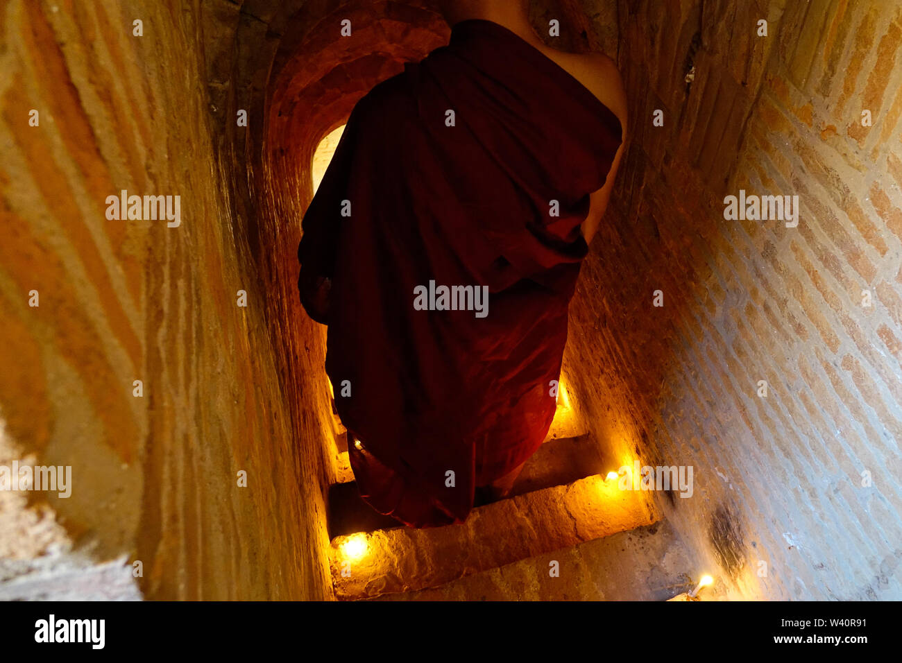 A young monk going downstairs of ancient brick Buddhist pagoda in Bagan ...