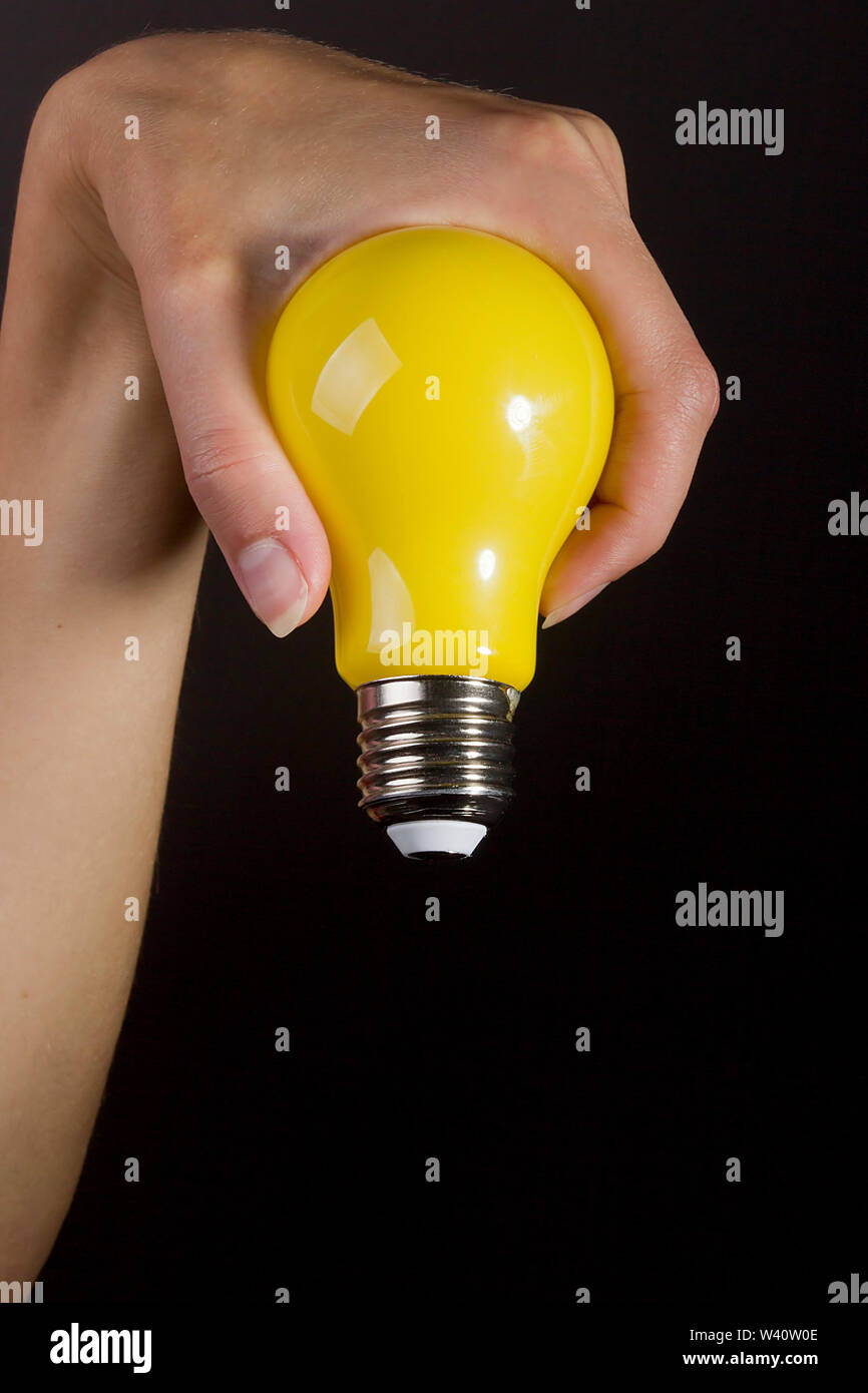 Female hand with a yellow light bulb Stock Photo - Alamy