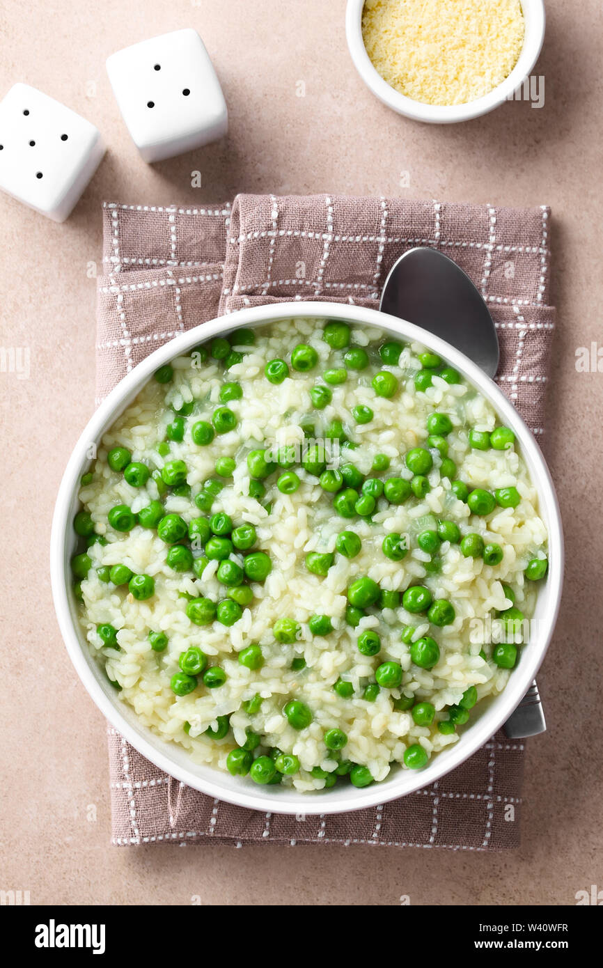 Fresh homemade creamy green pea risotto in bowl, spoon, spices and ...