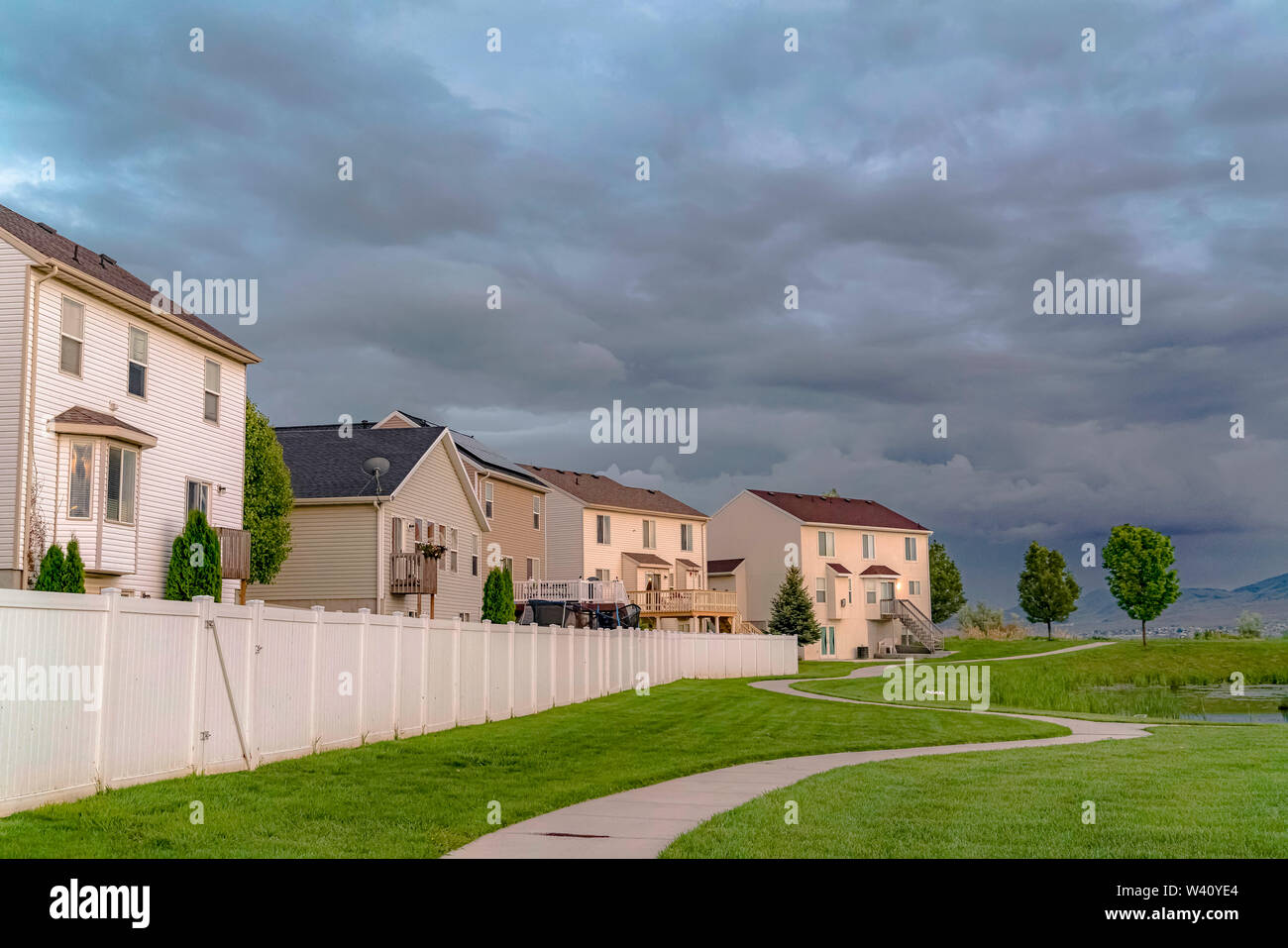 Home facade overlooking an expansive green field with a paved pathway ...