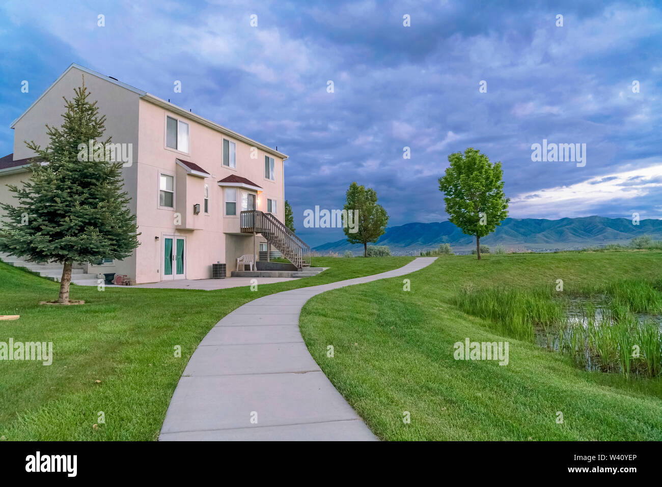 Scenic landscape with a home overlooking a pond and pathway on a grassy ...