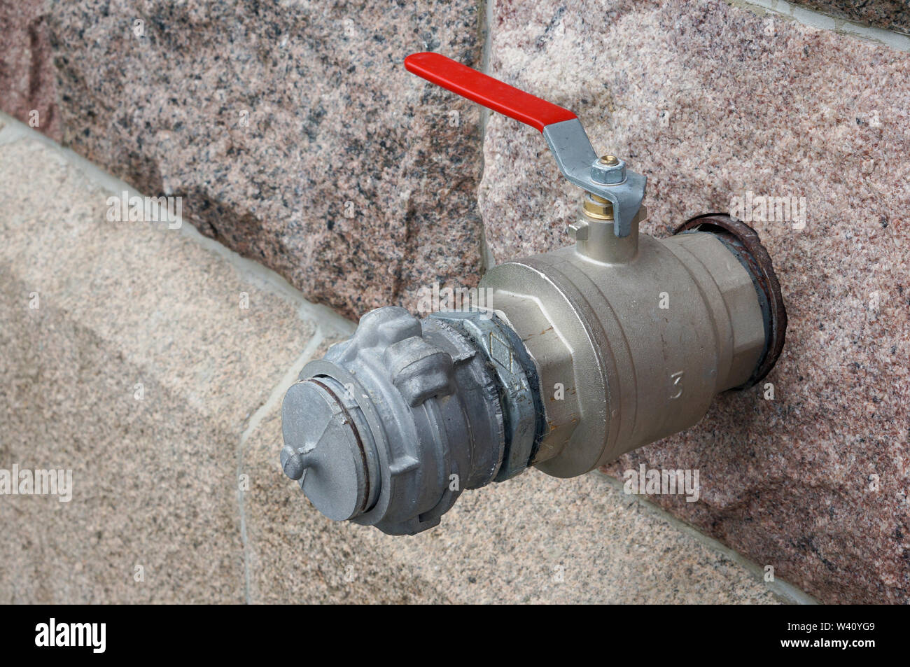 Fire hydrant and water tap reeled into a granite wall of an old house ...