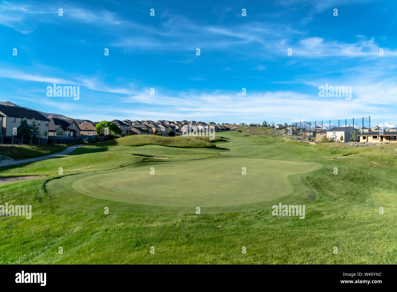 Golf course with view of lovely homes and mountain under blue sky with ...