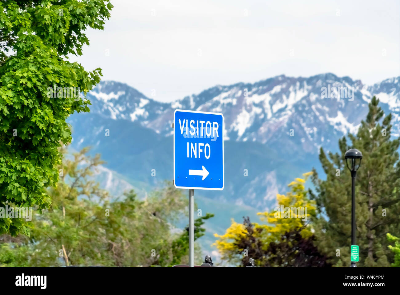 Close up of a Visitor Info sign with trees snowy mountain and sky ...