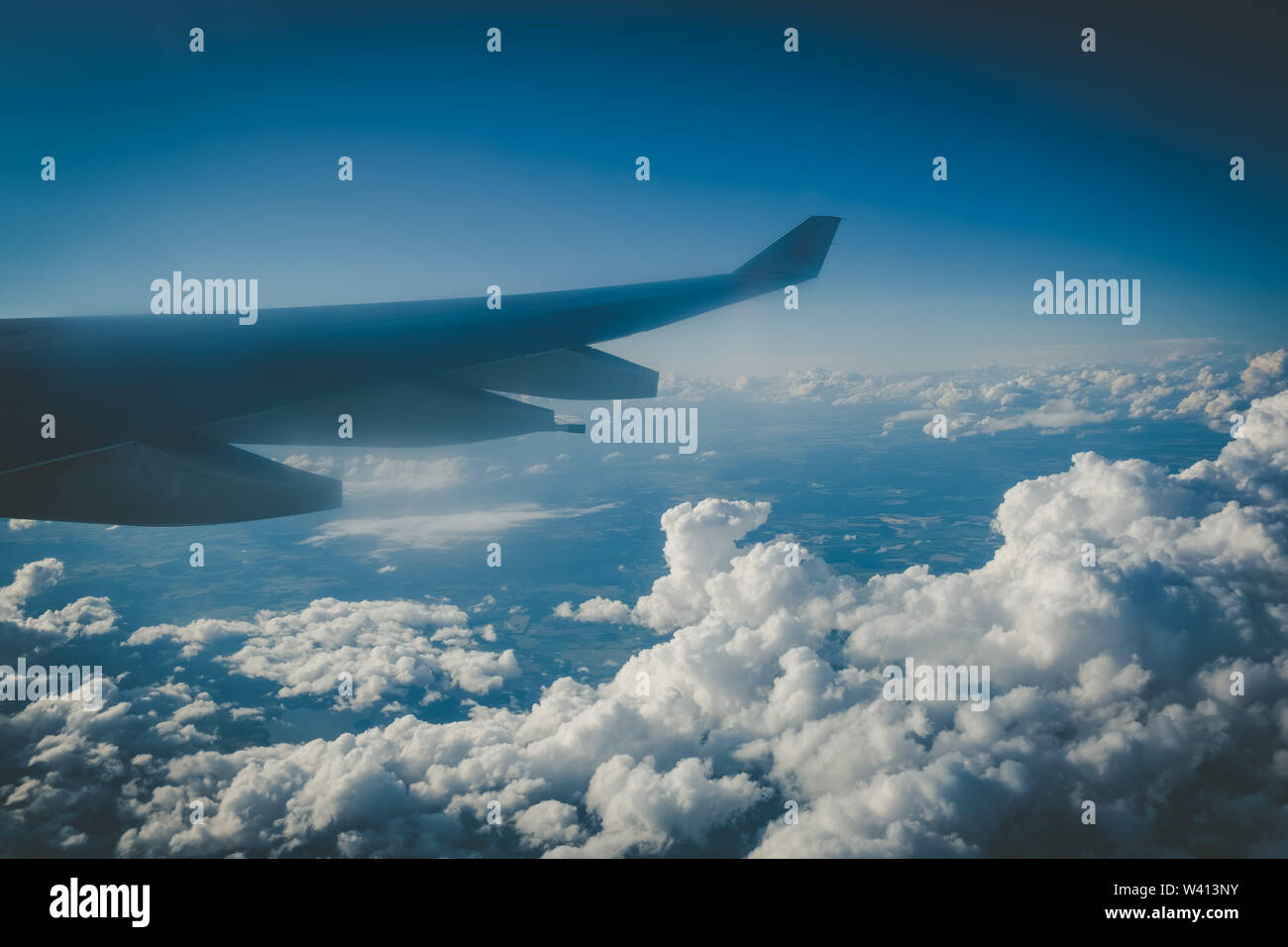 Wing of large passenger jet in mid flight above fluffy clouds and ...