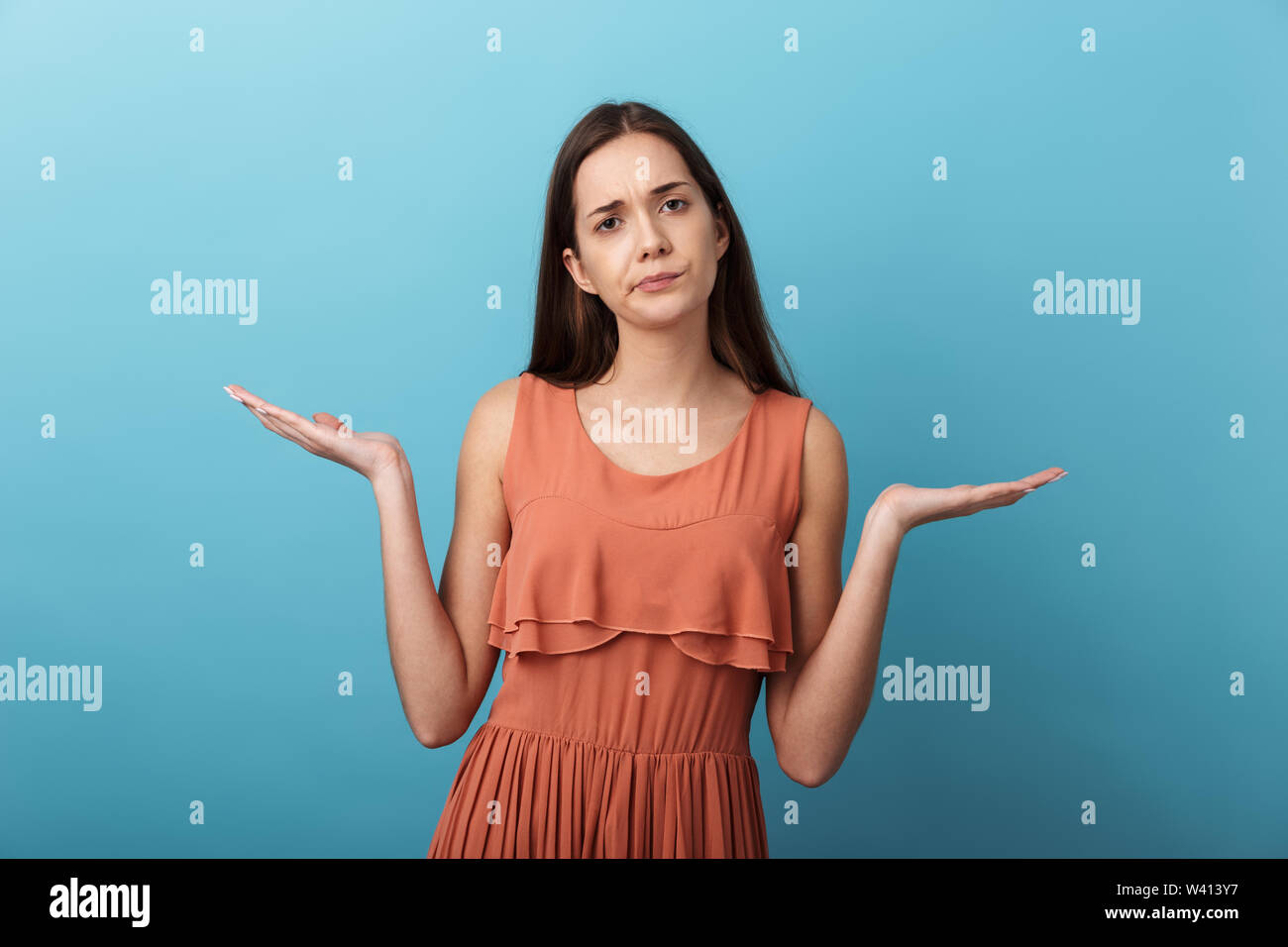Cute confused lovely young girl standing isolated over blue background ...