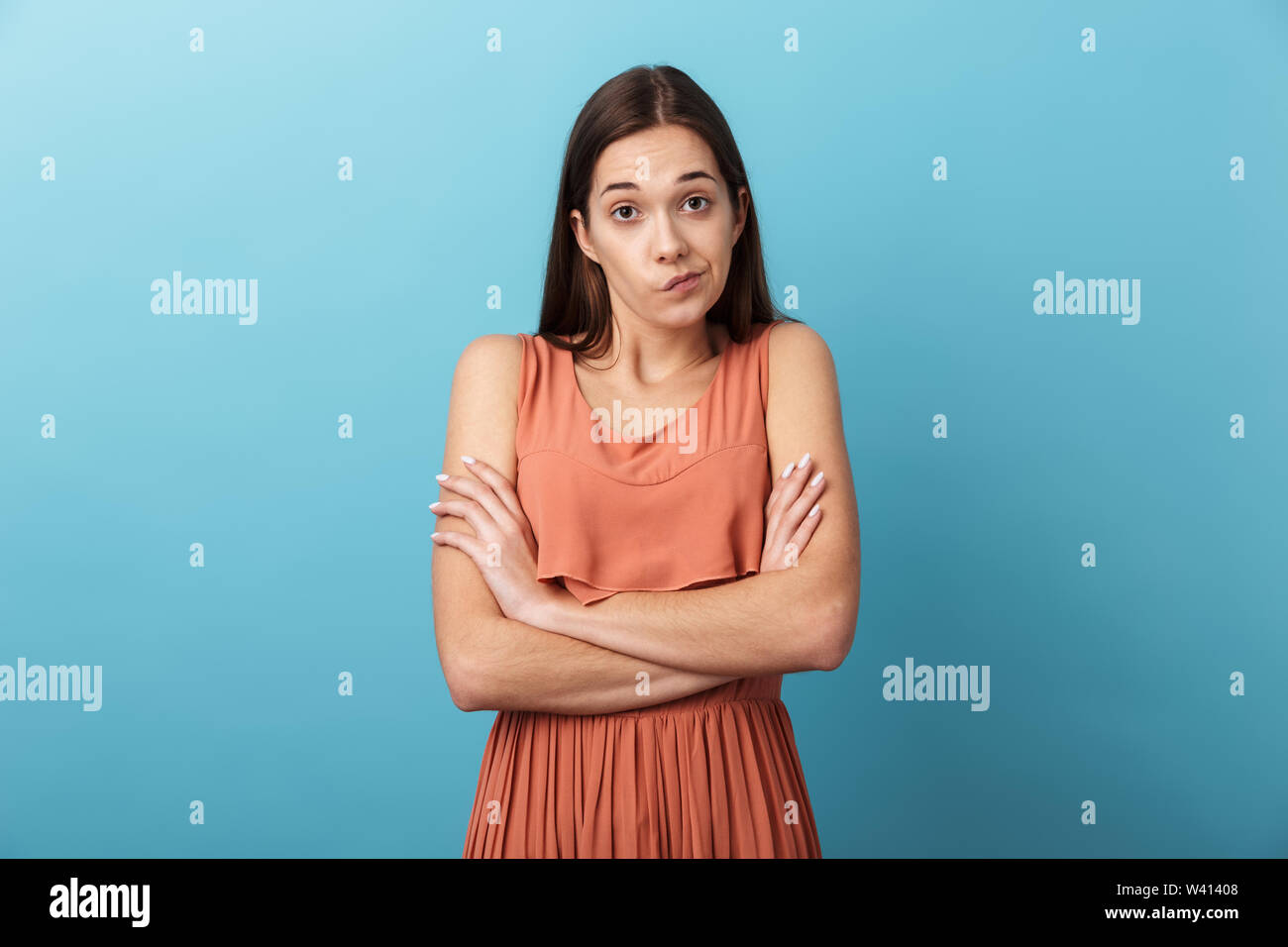 Cute confused lovely young girl standing isolated over blue background ...