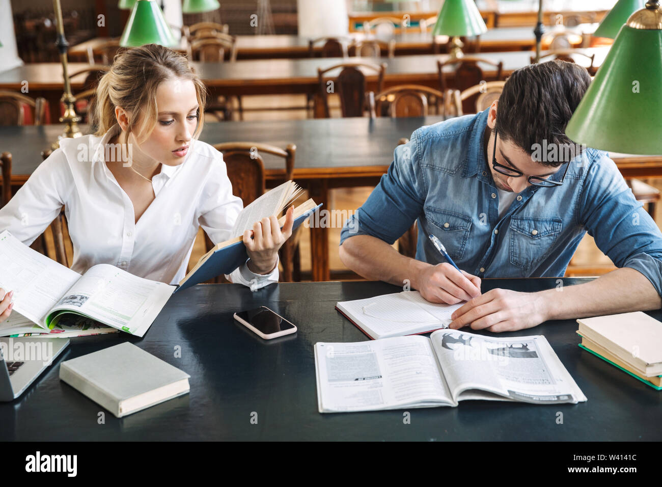 Group of smart young students studying hard at the library, using ...