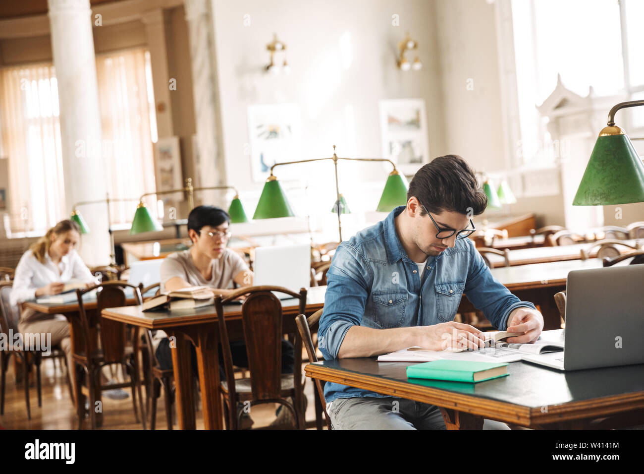 Group of smart young students studying hard at the library, using ...