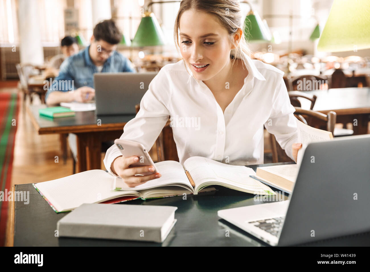 Pretty young smart girl student studying at the library Stock Photo - Alamy