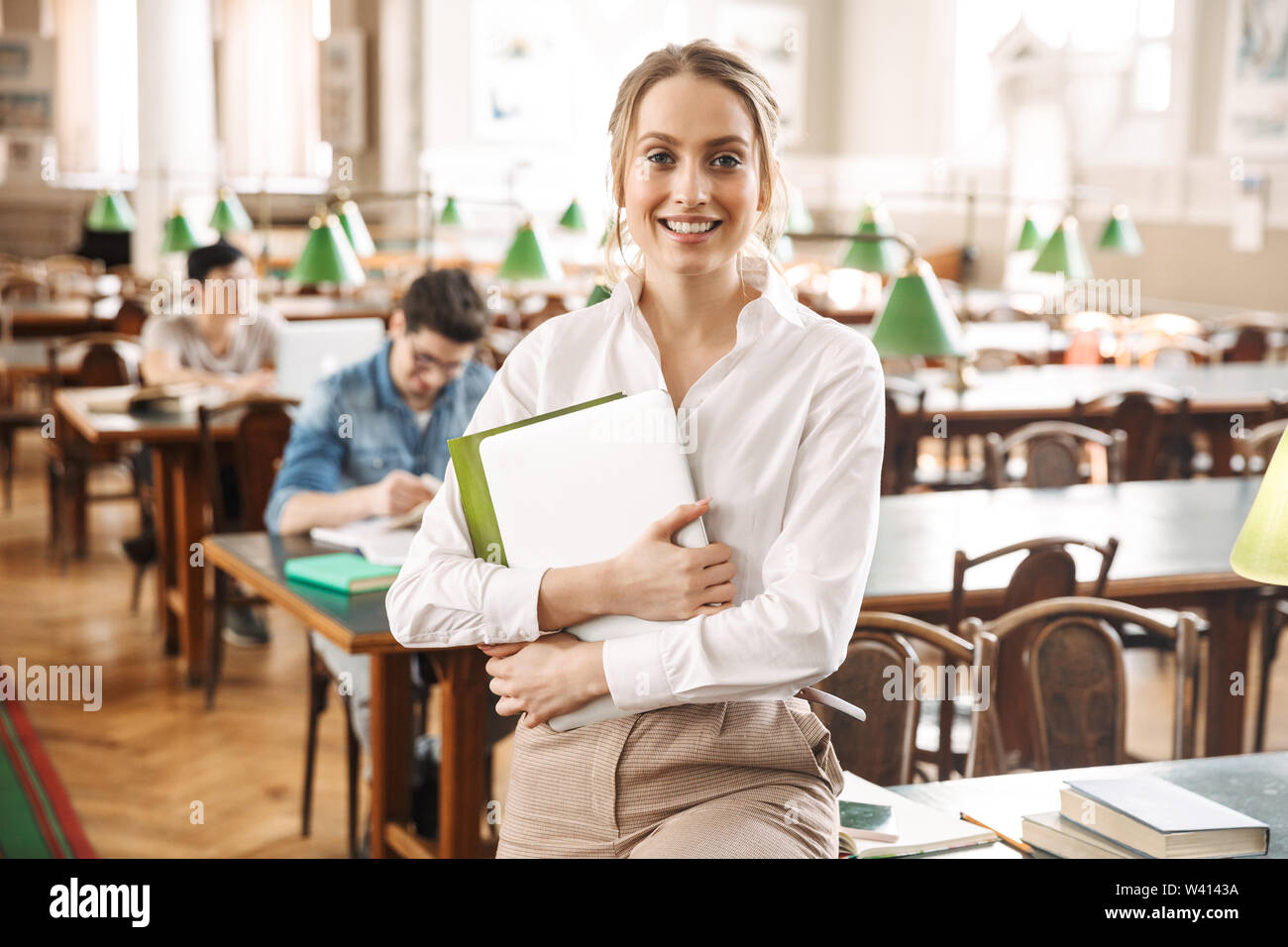 Pretty young smart girl student studying at the library Stock Photo - Alamy