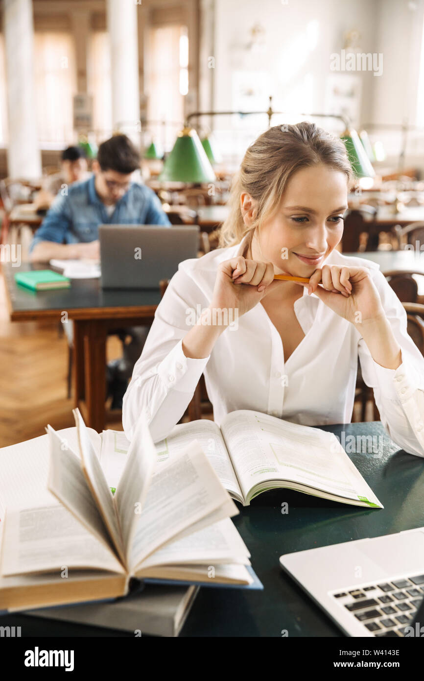 Pretty young smart girl student studying at the library Stock Photo - Alamy
