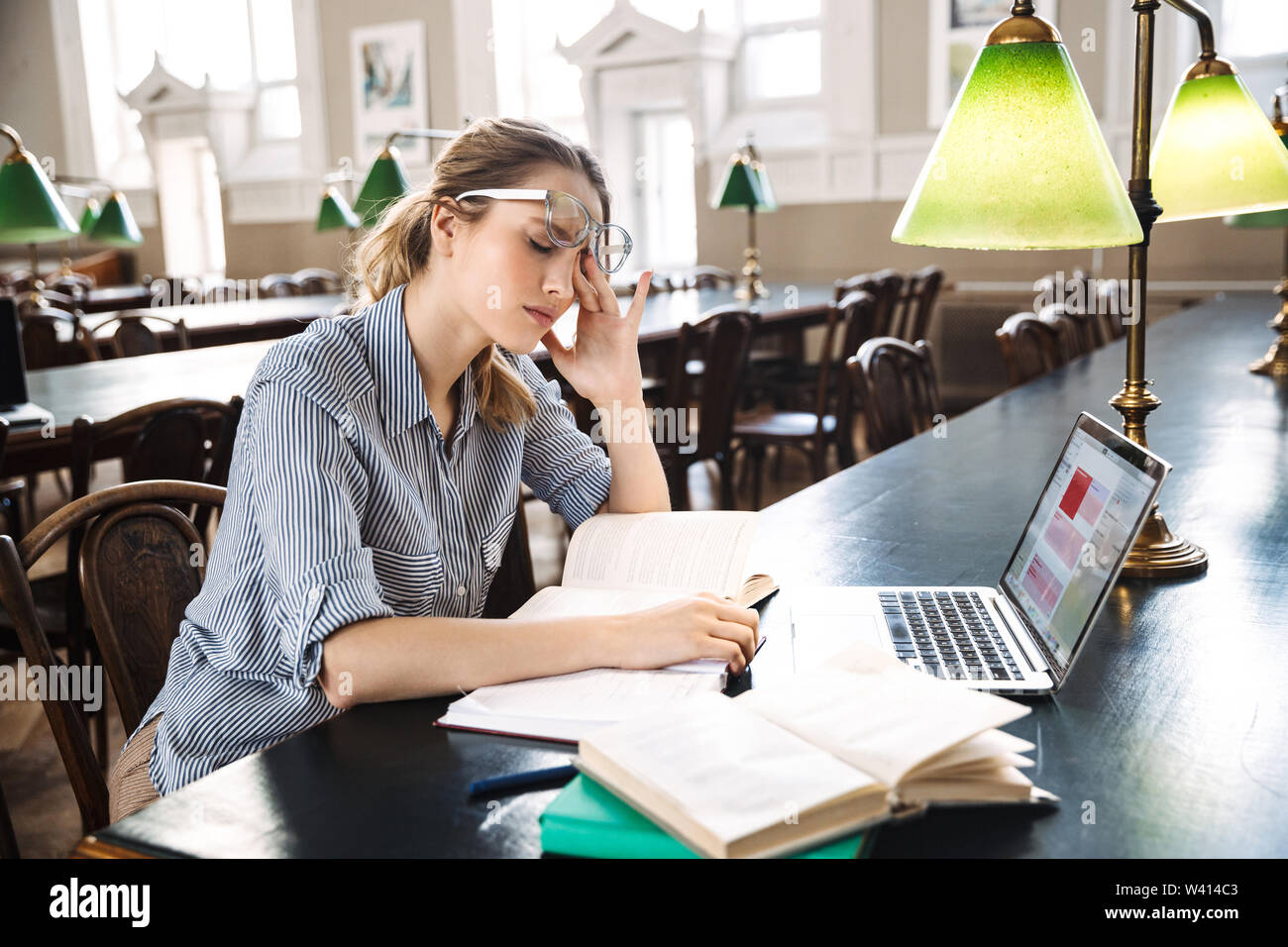 Tired student girl studying at the library Stock Photo - Alamy