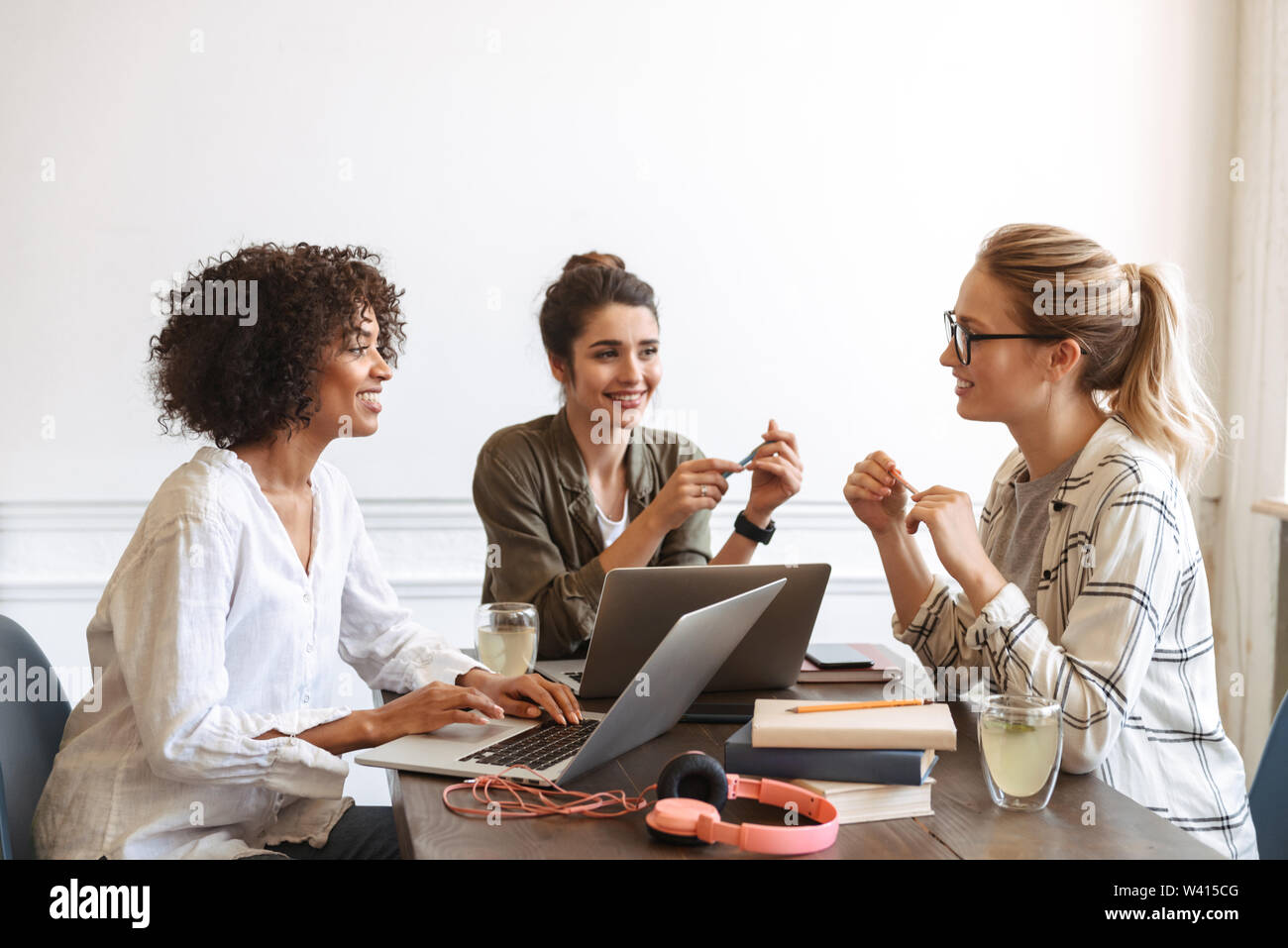 Group of multiethnic cheerful young women studying together at the ...