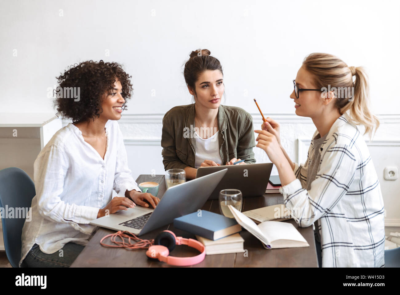 Group of multiethnic cheerful young women studying together at the ...