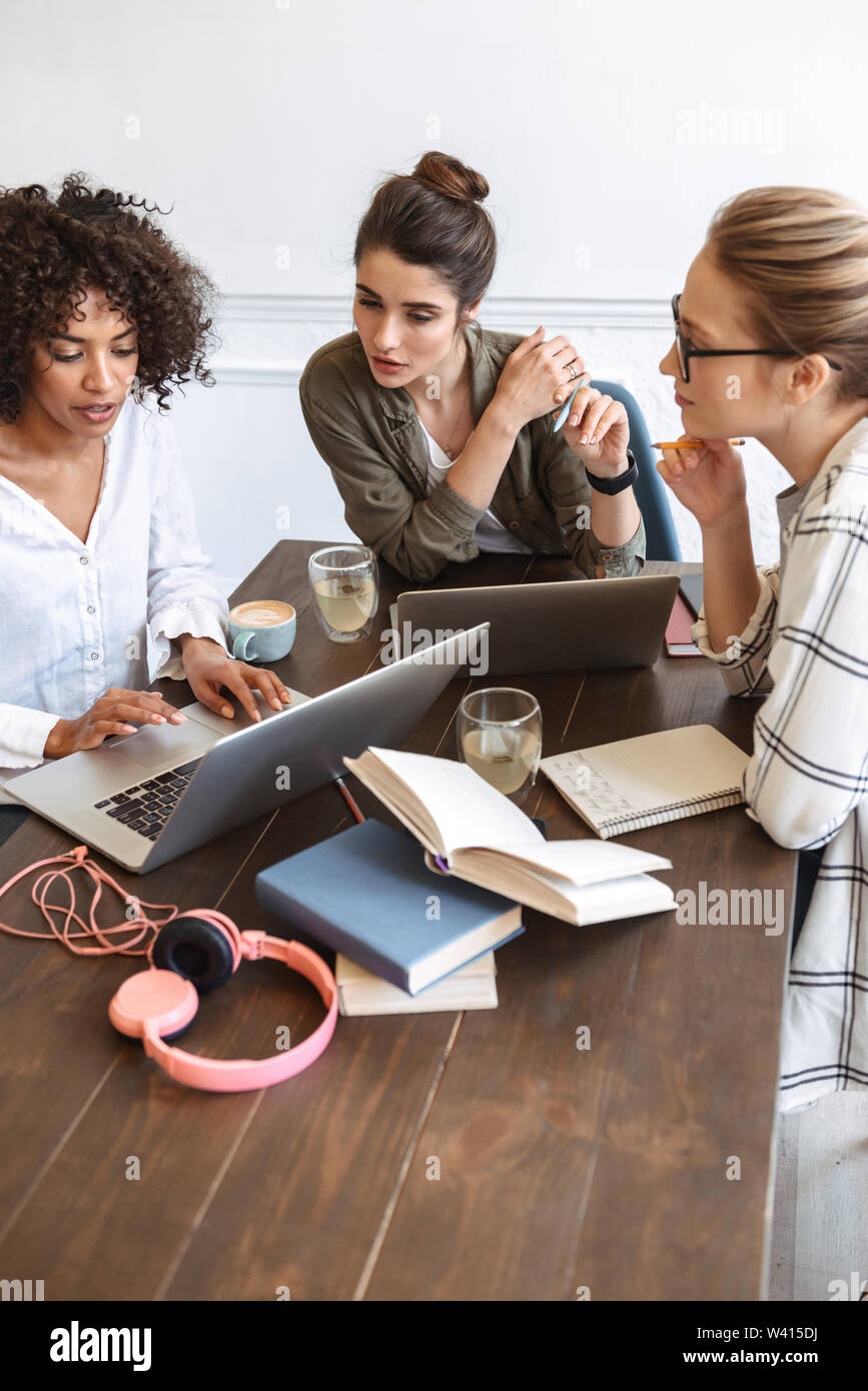Group of multiethnic cheerful young women studying together at the ...