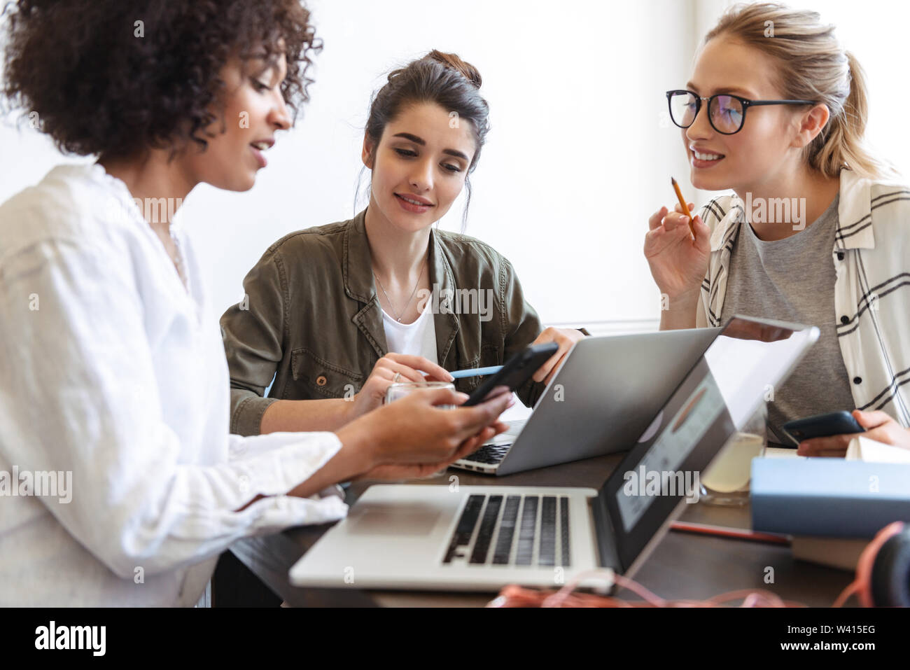 Group of multiethnic cheerful young women studying together at the ...