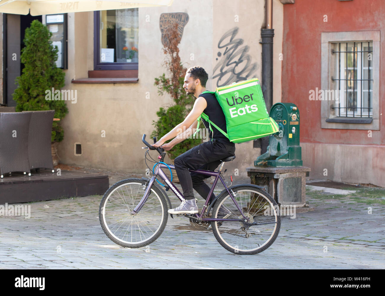Uber biker riding a bicycle. Old town in background. Poznan / Poland ...