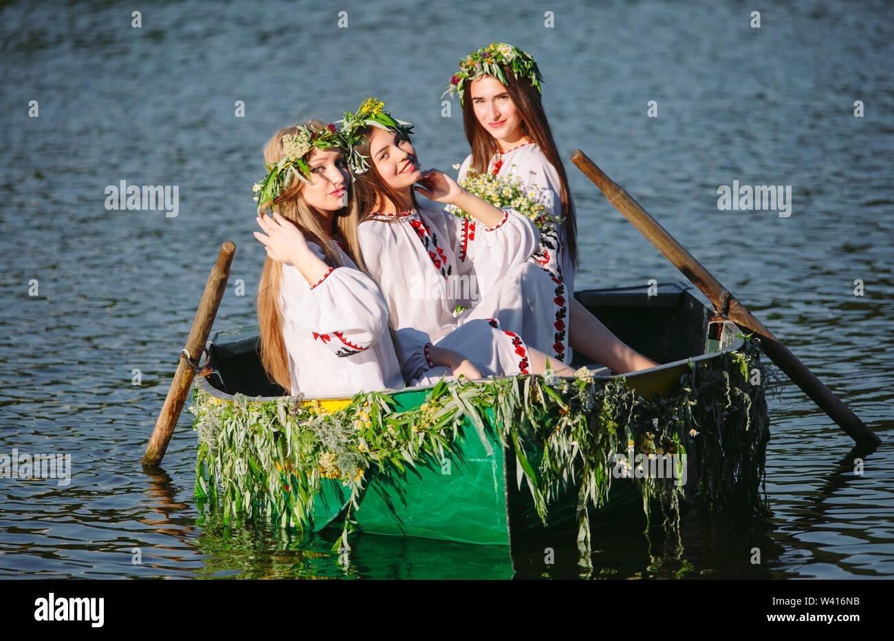 Midsummer. Young Girls in national costumes sail in a boat that is ...