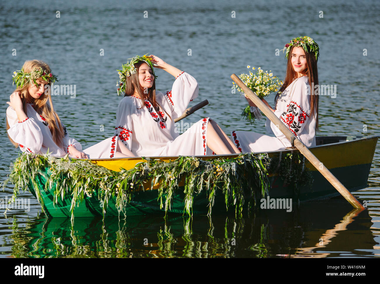 Midsummer. Young Girls in national costumes sail in a boat that is ...
