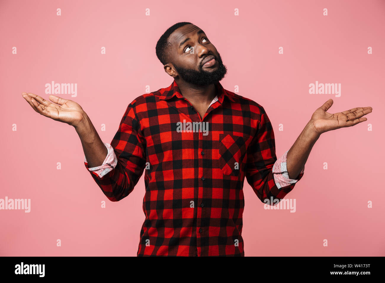 Portrait of a confused african man wearing plaid shirt standing ...