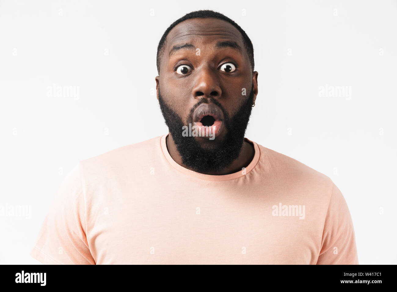 Portrait of a shocked african man wearing in t-shirt standing isolated ...