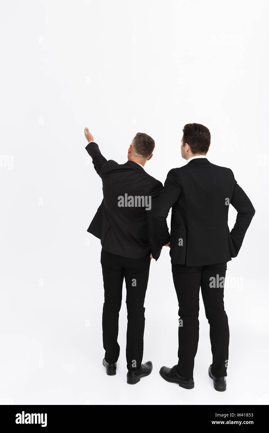 Back view of two confident businessmen wearing suits standing isolated ...