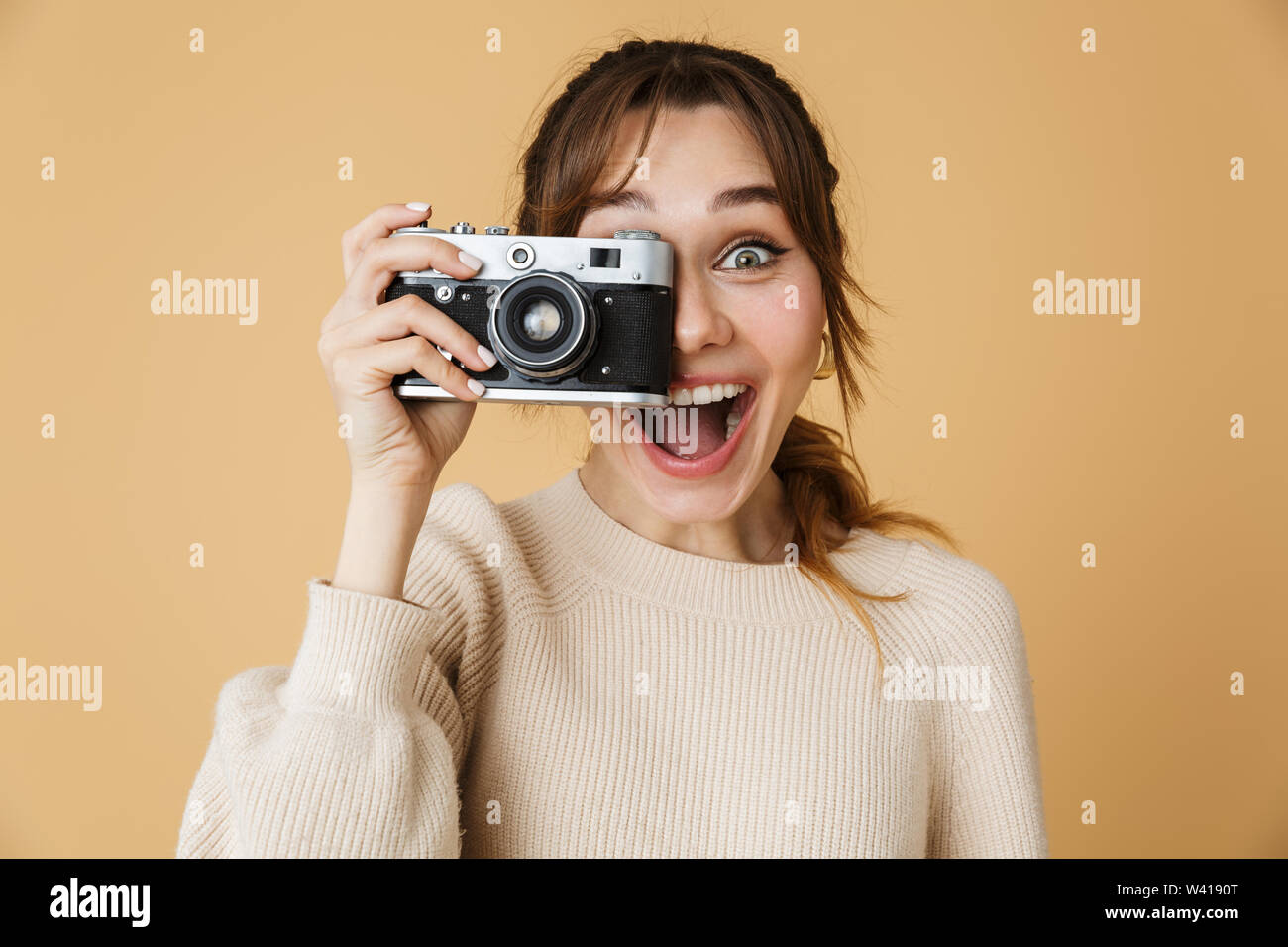 Attractive young woman wearing sweater standing isolated over beige ...