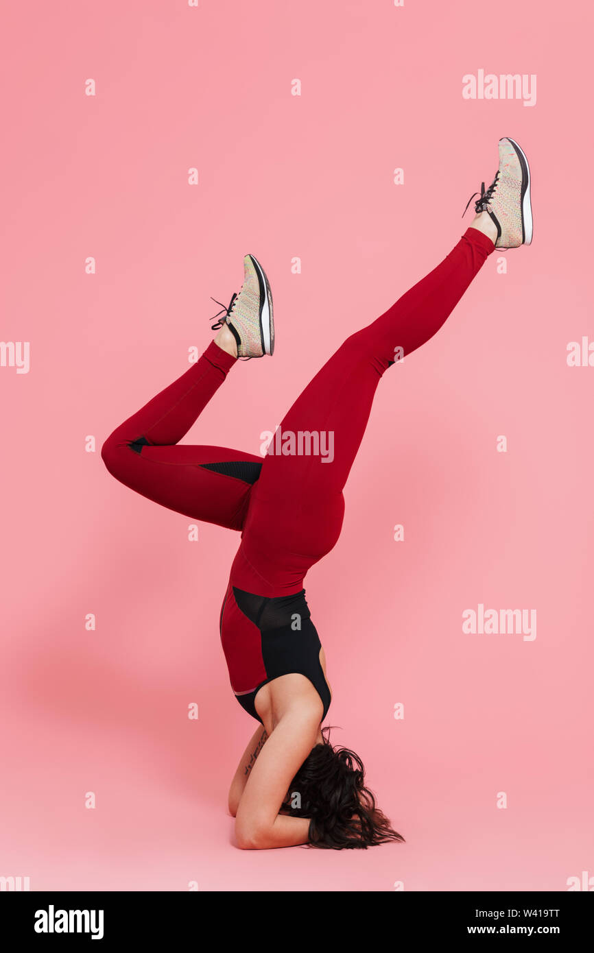 Full length portrait of a fit beautiful sports woman doing exercises isolated over pink ...