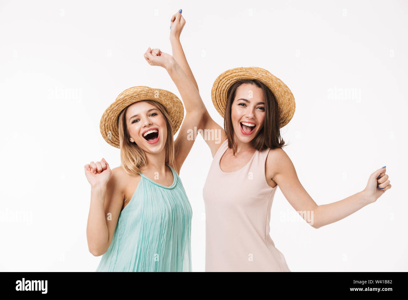 Two cheerful young girls wearing summer clothes standing isolated over ...