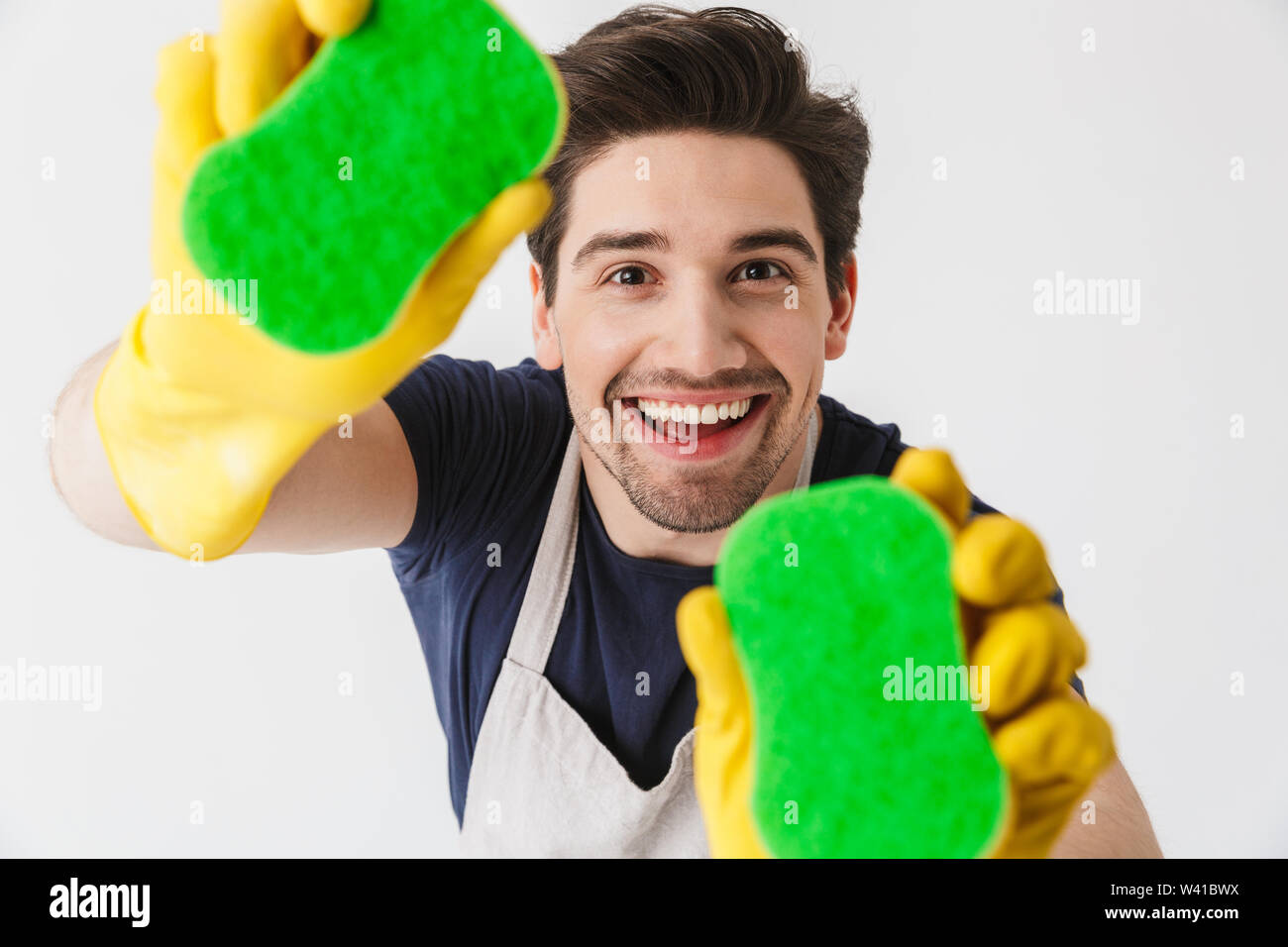 Handsome brunette houseman wearing apron standing isolated over white ...