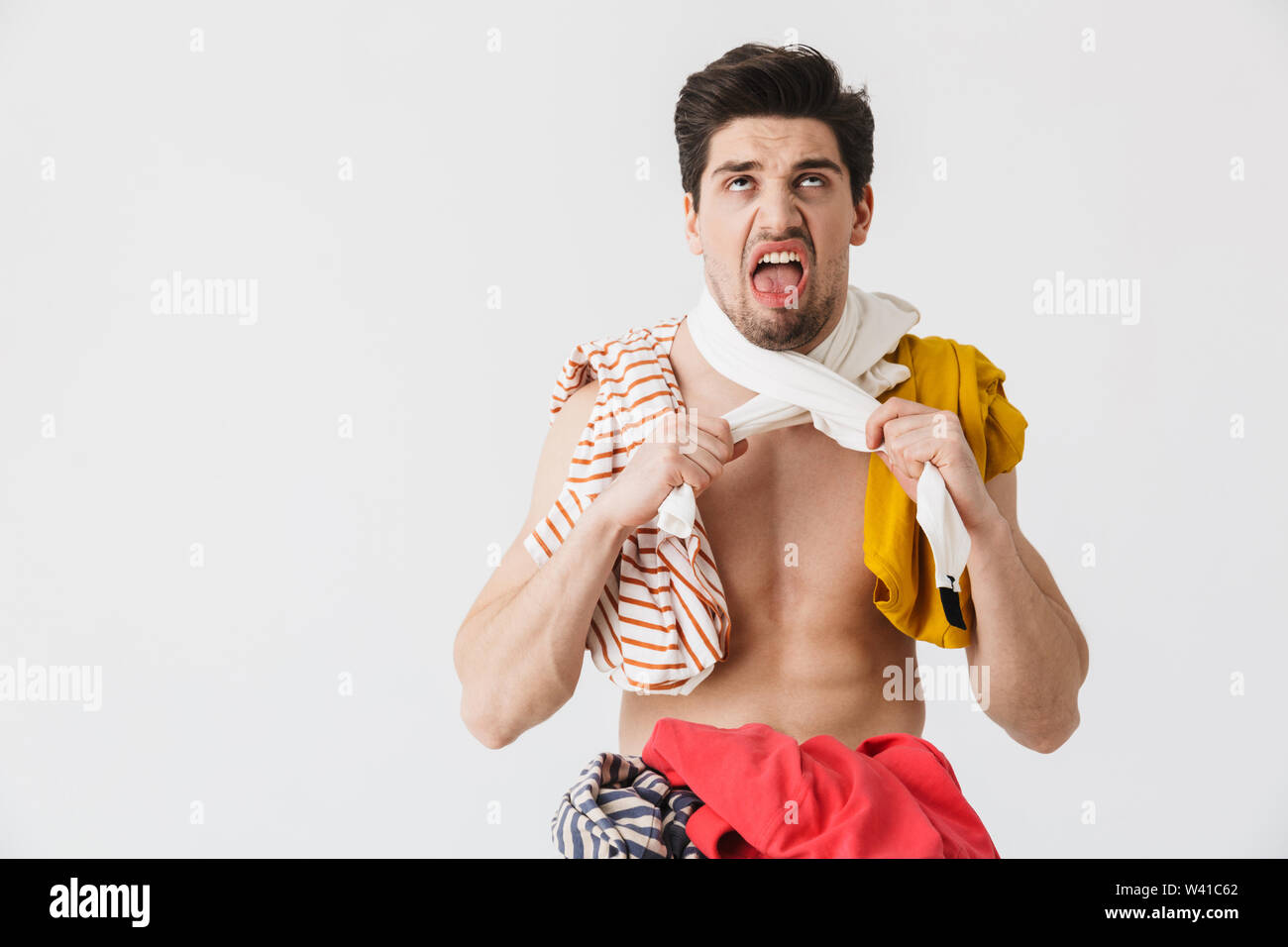 Handsome angry brunette houseman wearing apron standing isolated over ...