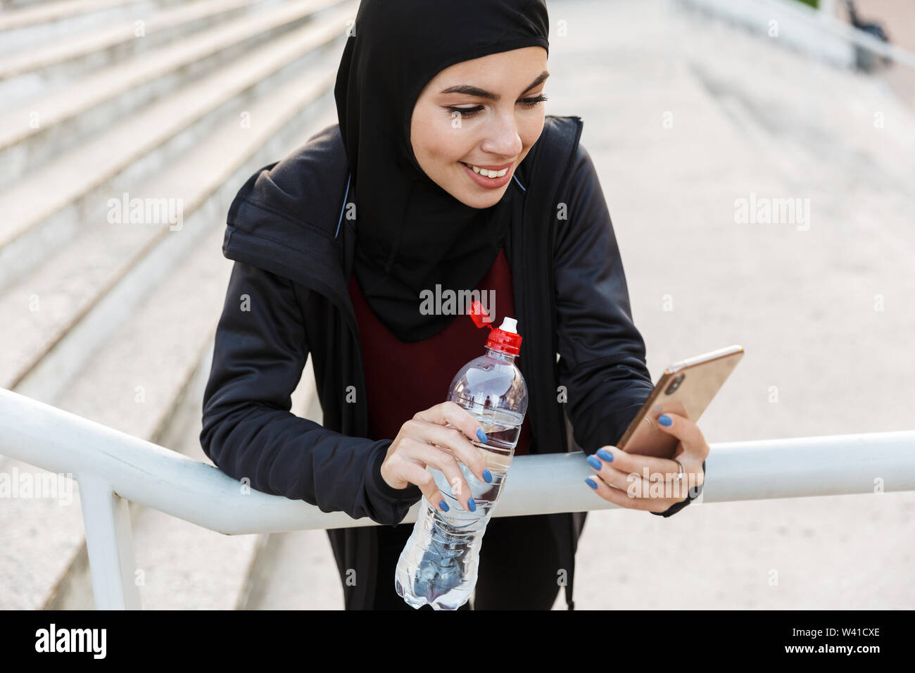 Photo of a young smiling happy muslim sports fitness woman dressed in ...