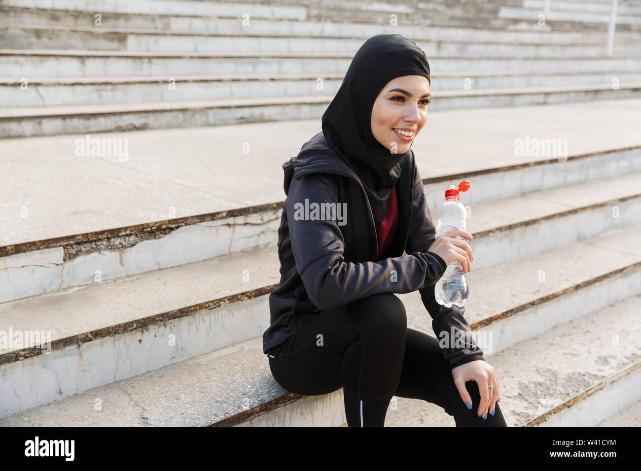 Image of a young cheerful happy muslim sports fitness woman dressed in ...