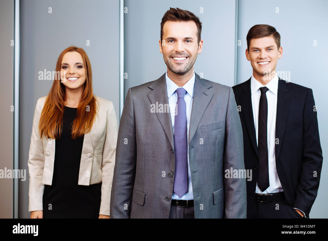 Three happy business people standing in office Stock Photo - Alamy