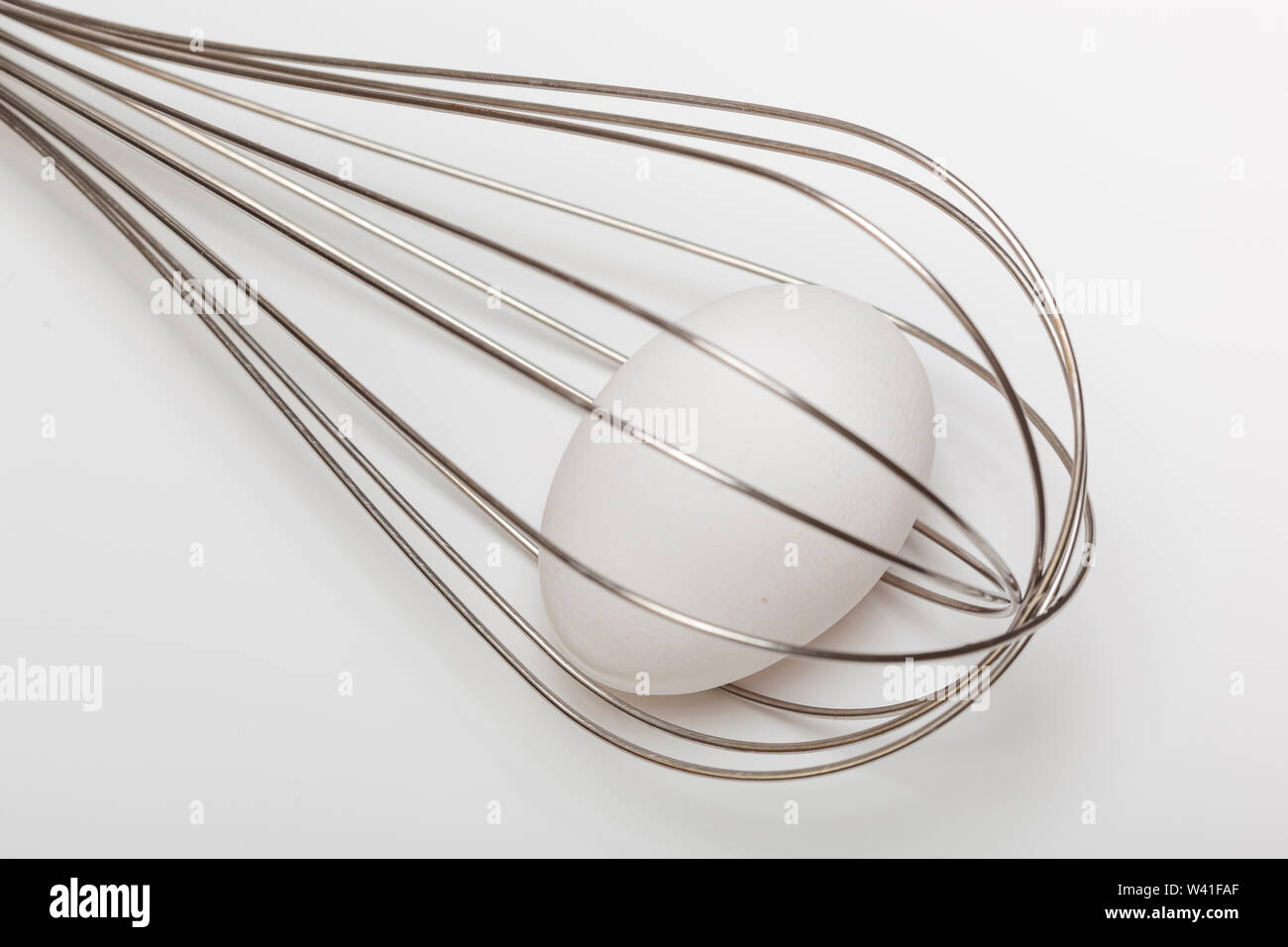 Wire stirring eggs on white Stock Photo - Alamy