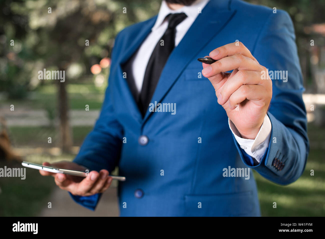 Businessman holds pen and points into copy space. Man with lap top and ...