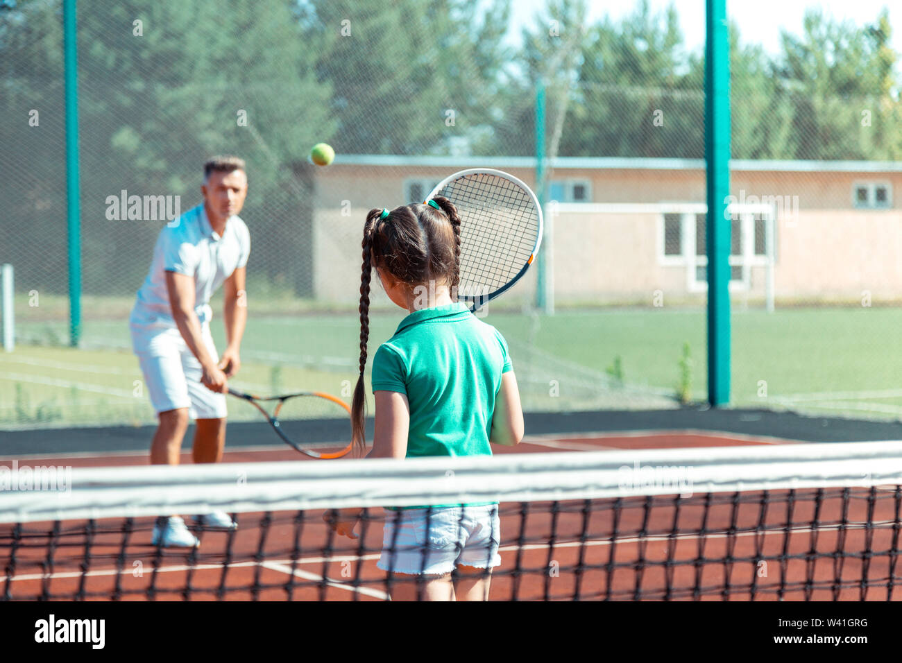 Daughter feeling involved in playing tennis with father Stock Photo - Alamy