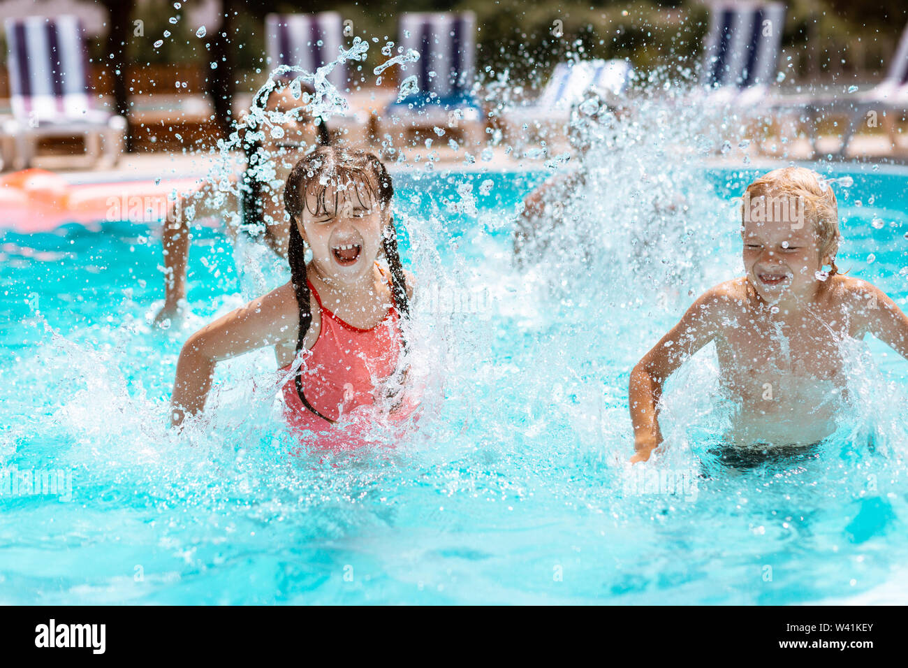 Children laughing while splashing water in swimming pool Stock Photo ...