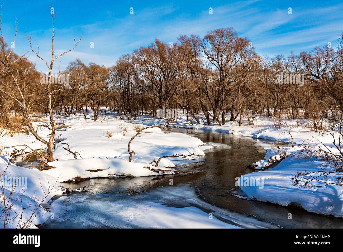Small river in the spring in the forest, the shores in the snow. Part ...
