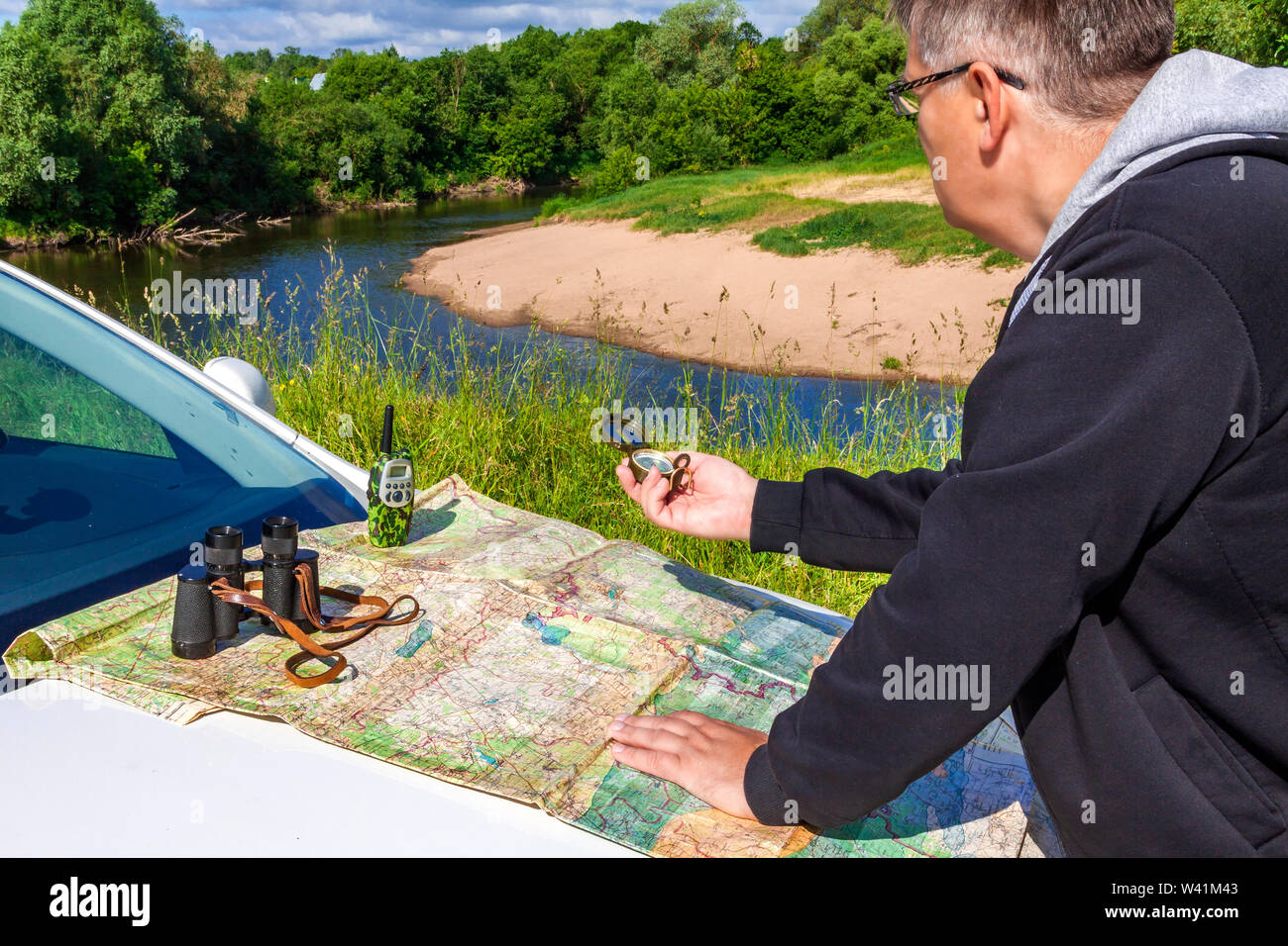 A man checking the terrain on a map with a compass Stock Photo - Alamy