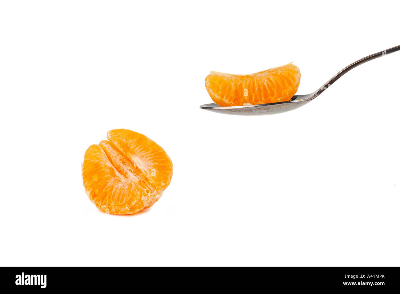 A spoon holds a slice of mandarin on a white background Stock Photo - Alamy
