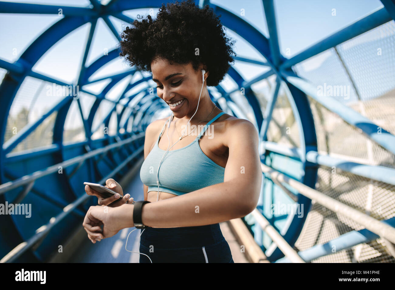 Fit female runner using smart watch and mobile phone to monitor her ...