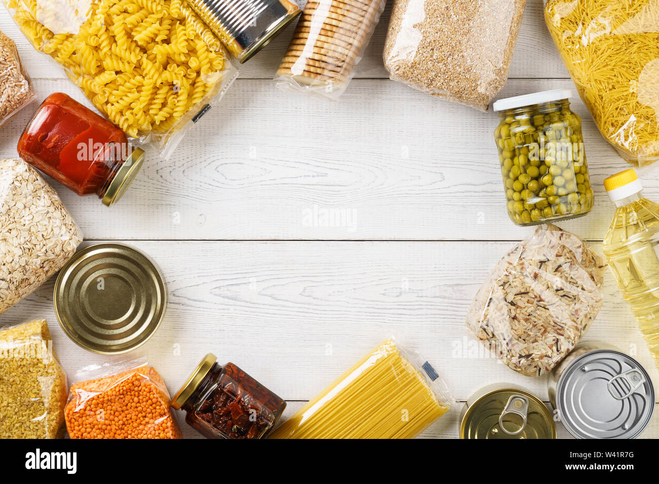 Various uncooked cereals, grains, pasta and canned food on a white ...