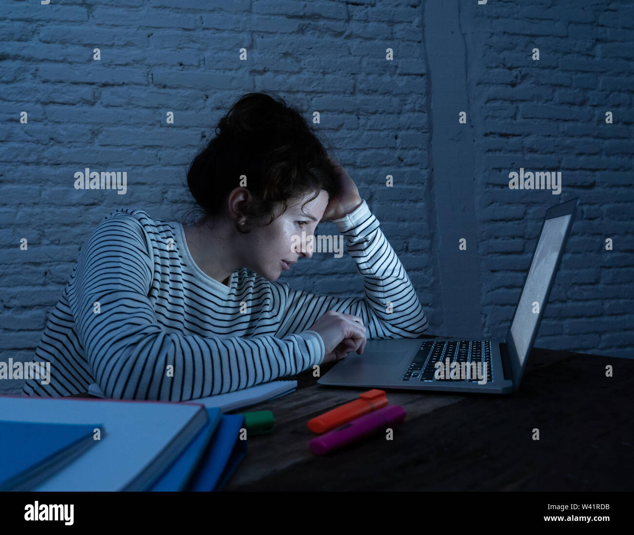 Overworked and tired female student working late at night on her laptop ...