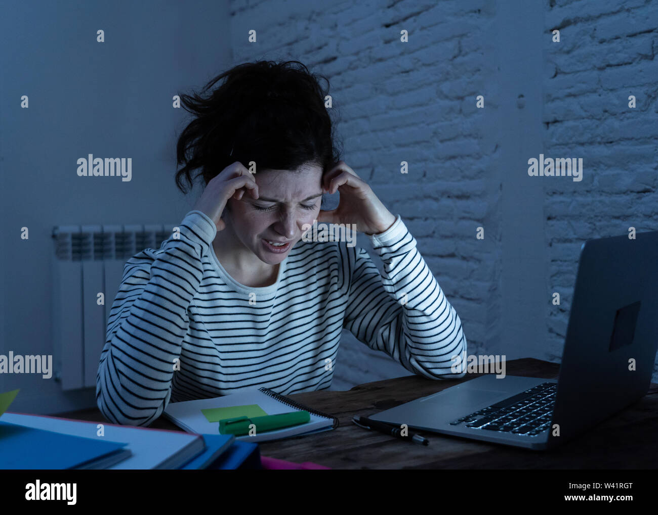 Overworked and tired female student working late at night on her laptop ...
