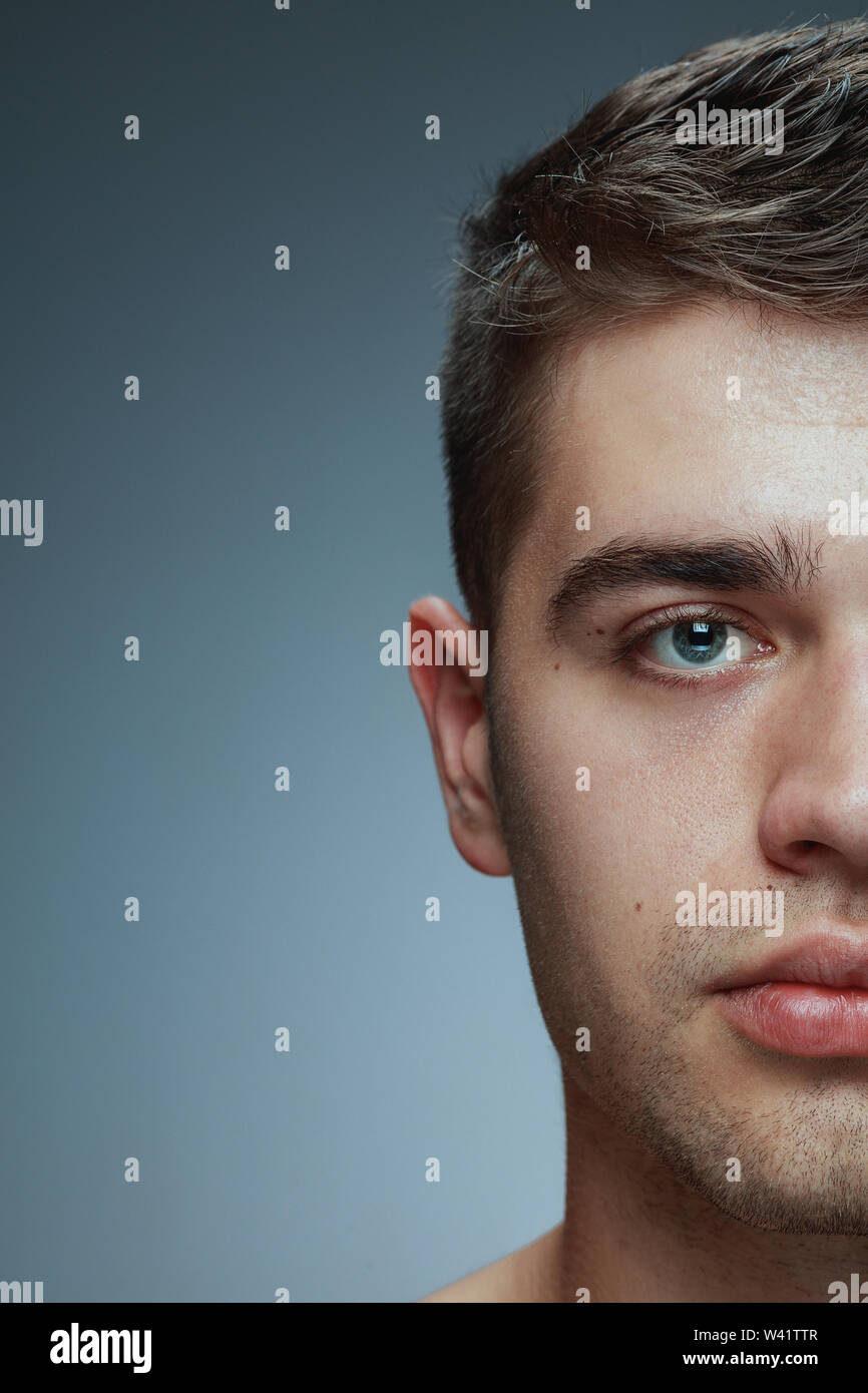 Close-up portrait of young man isolated on grey studio background ...