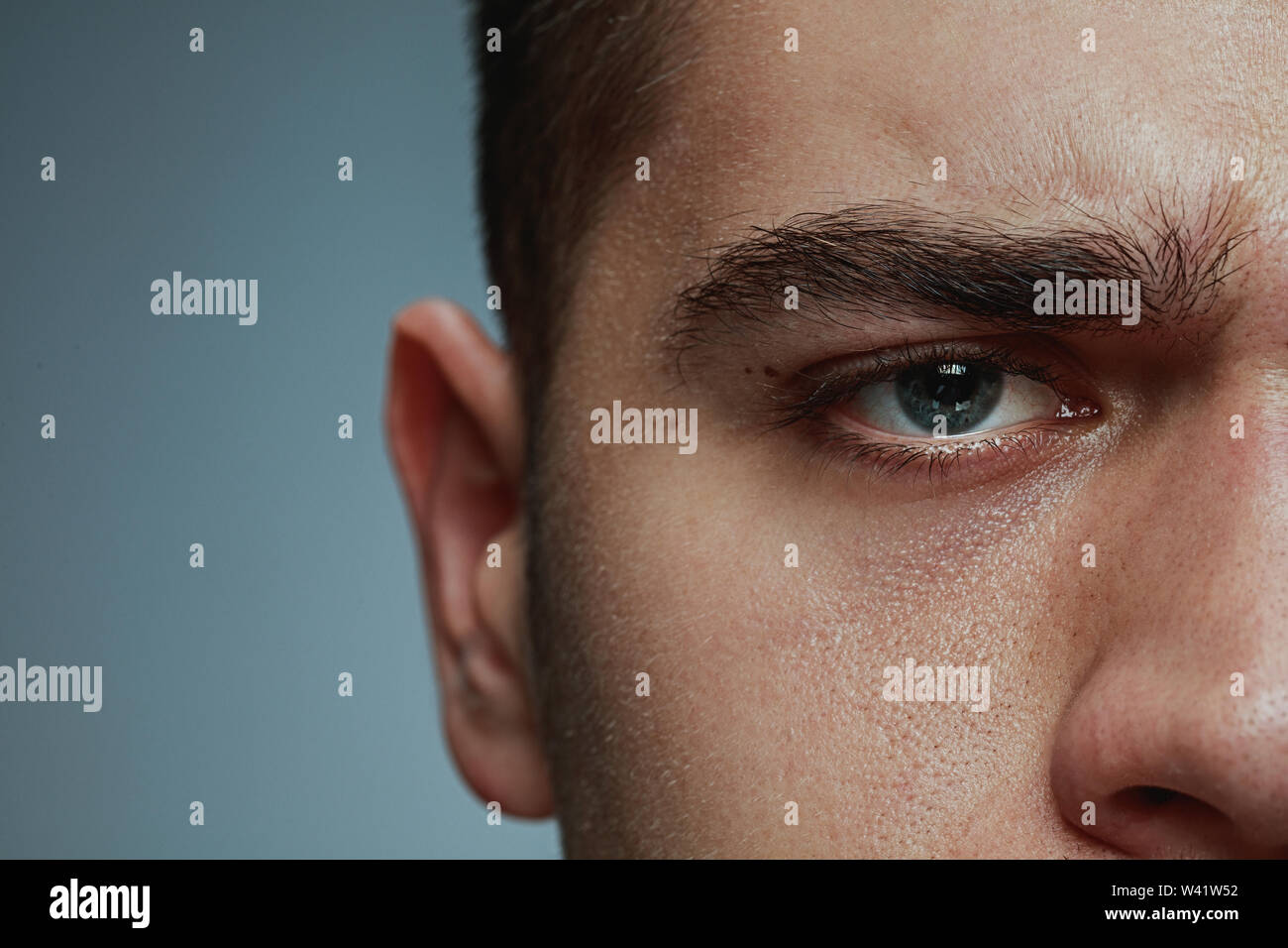 Close-up portrait of young man isolated on grey studio background ...