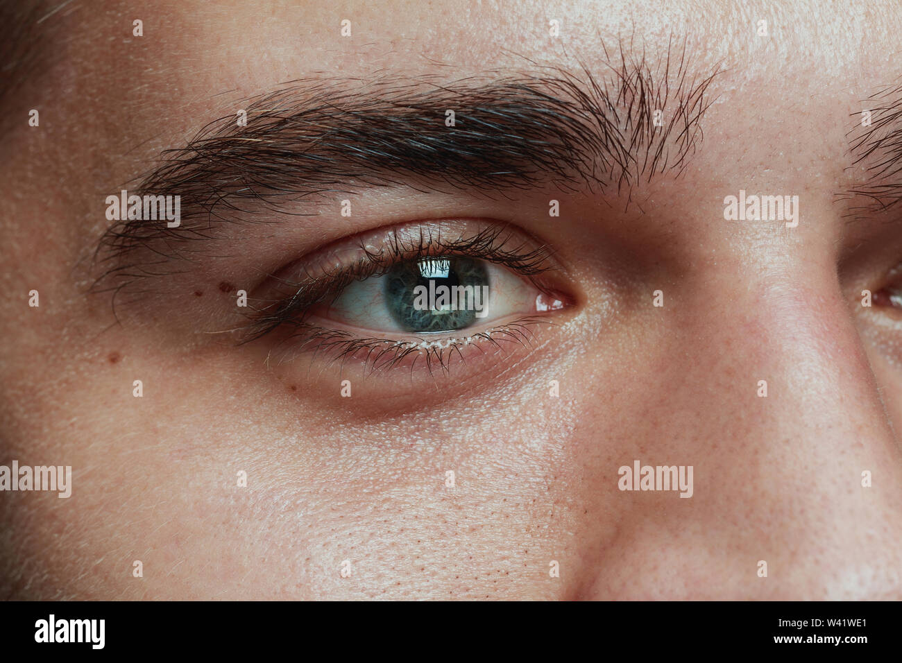 Close-up portrait of young man isolated on grey studio background ...